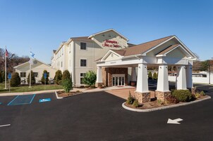 Um Hampton Inn & Suites com entrada coberta, estacionamento acessível para pessoas com deficiência e céu claro.