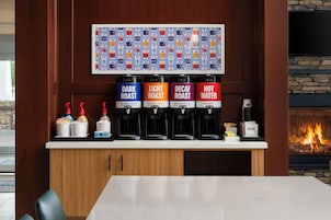 Estação de café com quatro dispensadores identificados como TORRA ESCURA, TORRA CLARA, DESCAFEINADO e ÁGUA QUENTE.