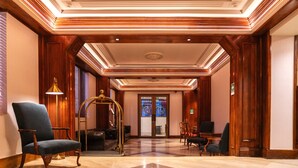 Um lobby com piso xadrez, lambris de madeira e um espelho grande.