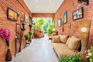 Um interior acolhedor com parede de tijolos, um sofá e diversas plantas.