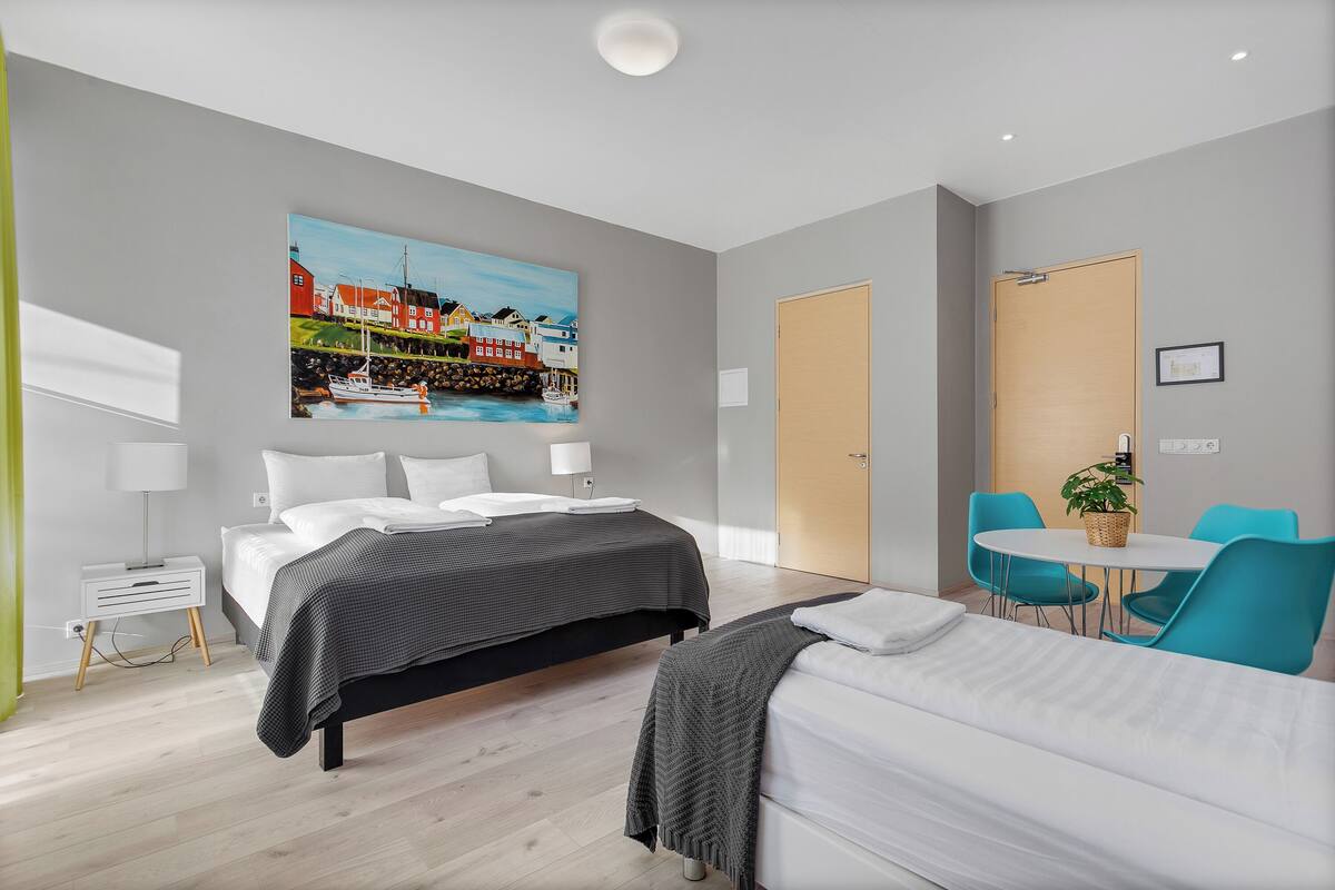 Quarto de hotel moderno com uma cama, mesas de cabeceira, escrivaninha e uma cadeira.