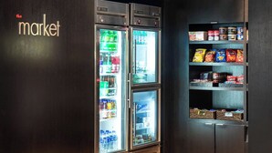 Um interior moderno com piso de madeira, um balcão refrigerado e uma prateleira repleta de lanches.