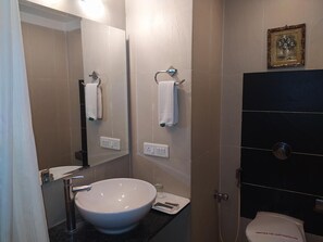 Um banheiro moderno com um espelho grande, uma pia branca, um porta-toalhas e um vaso sanitário.