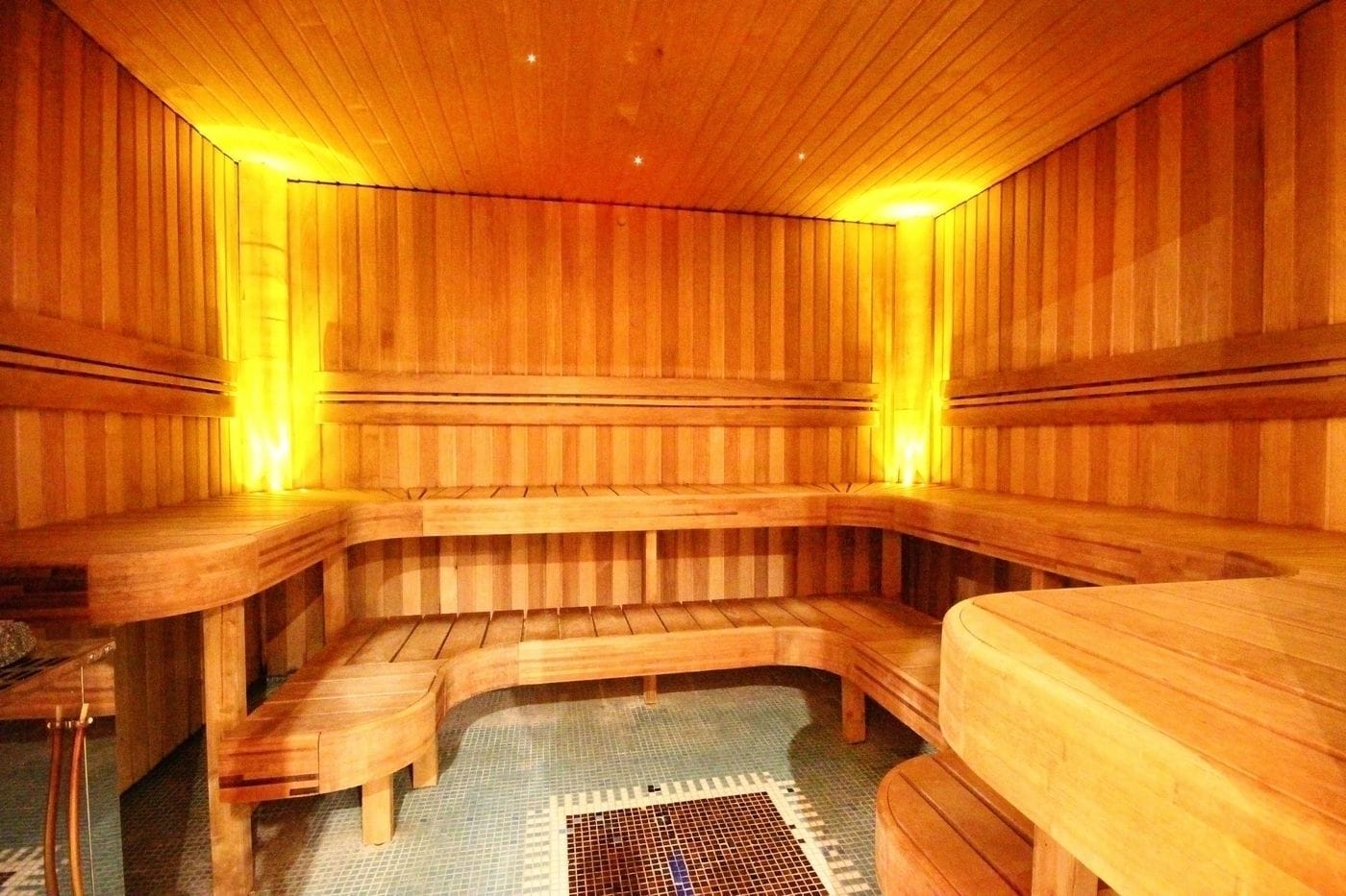 Uma sauna com bancos de madeira e piso ladrilhado.