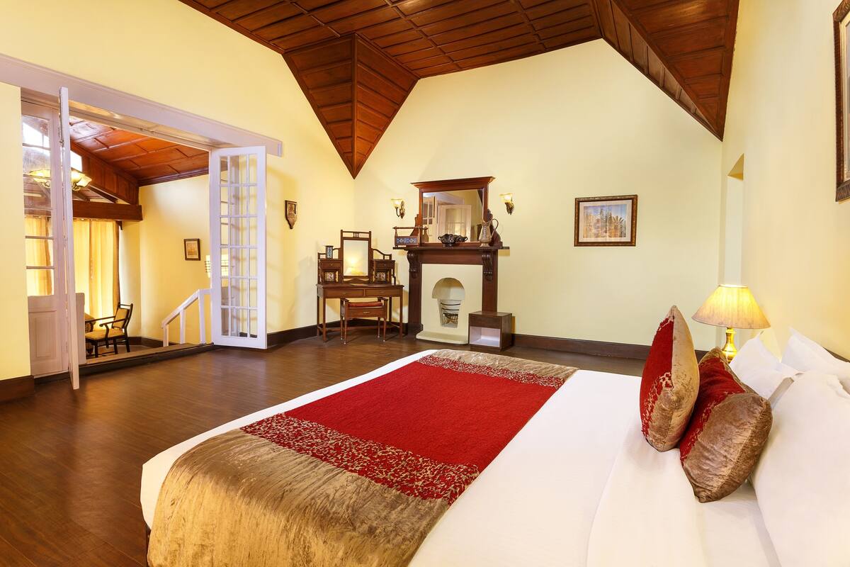 Quarto com cama grande, teto de madeira e lareira.