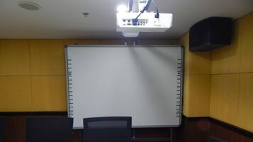 Sala de conferências com quadro branco, projetor e duas cadeiras.