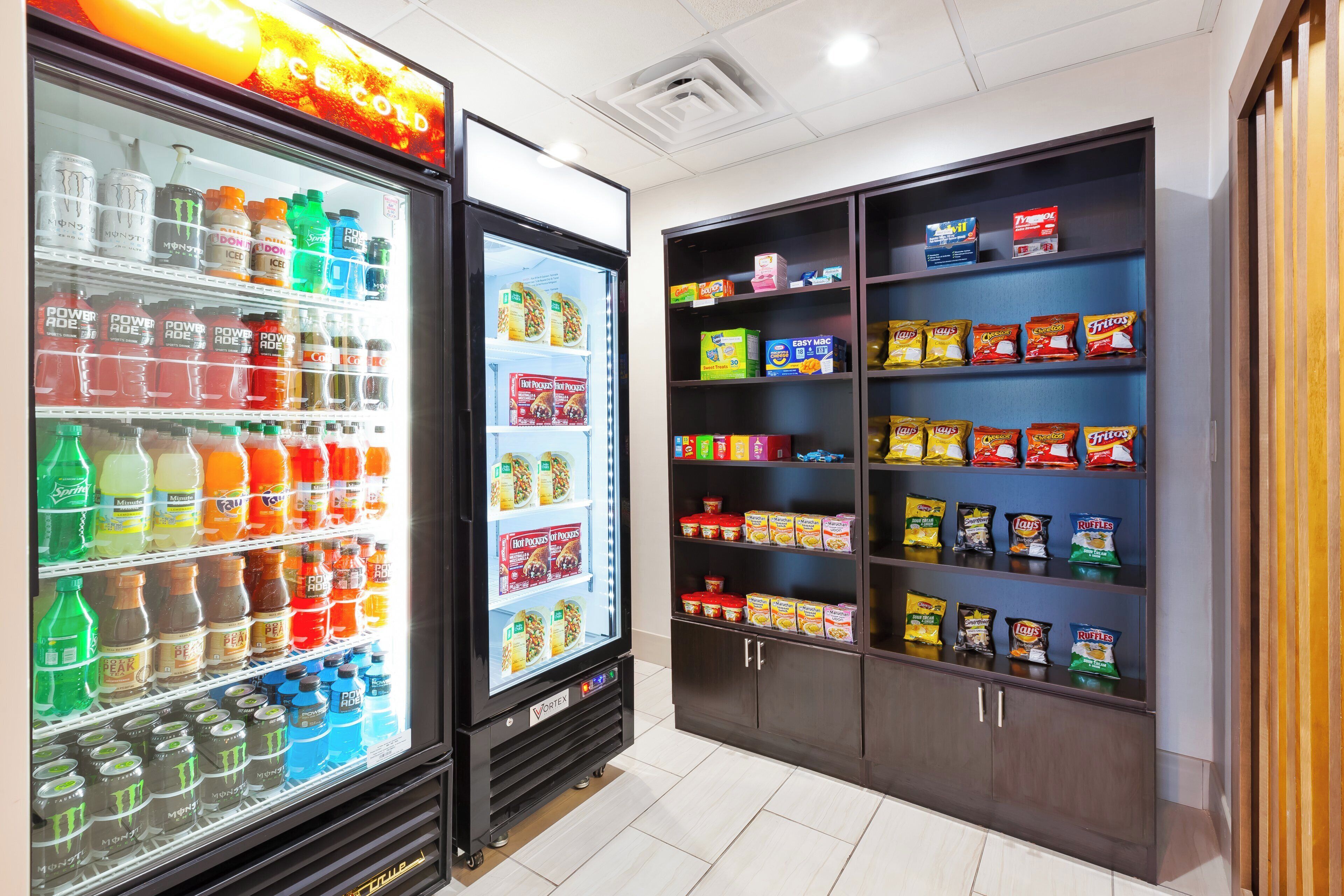 Máquina automática com diversas bebidas e lanches, e uma prateleira repleta de produtos embalados.