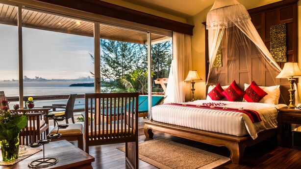 Quarto com uma cama grande, dossel e vista para o mar.