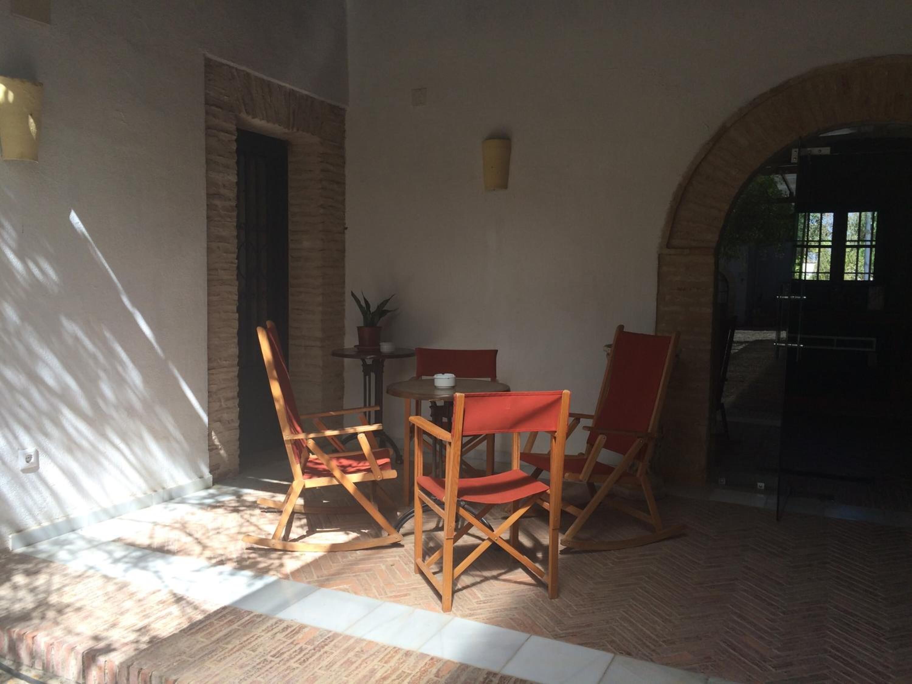 Um pátio com mesa, cadeiras, um vaso de planta e um muro de tijolos.