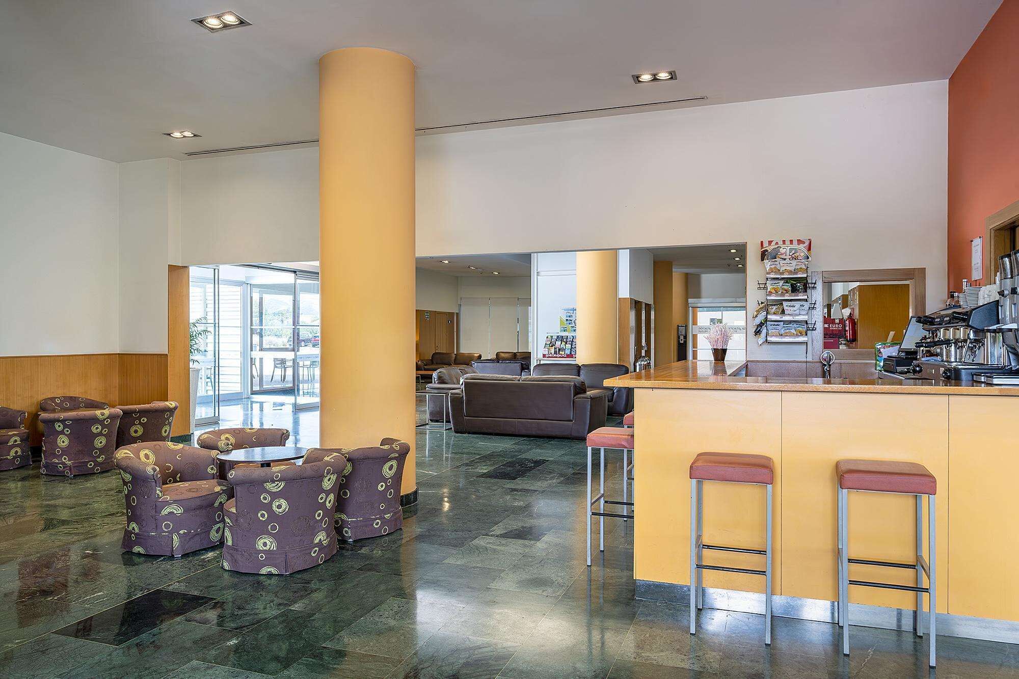Um hall amplo com área de bar central, disposição de assentos e um pilar grande.
