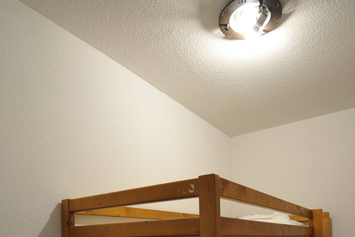Uma cama beliche em um quarto com paredes brancas e piso de madeira.
