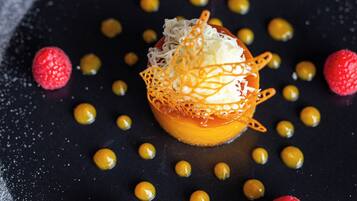 Sobremesa com prato preto, pontos amarelos e frutas vermelhas.