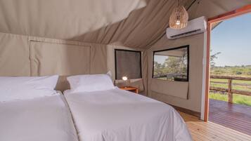 Um quarto amplo com tenda, uma cama grande, uma luminária de cabeceira e vista para o exterior.