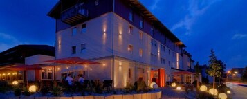 Hotel de vários andares com área de estar externa e janelas iluminadas.