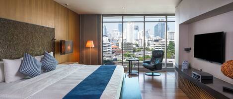 Quarto de hotel moderno com uma cama grande, vista para a cidade, televisão de tela plana e área de estar.