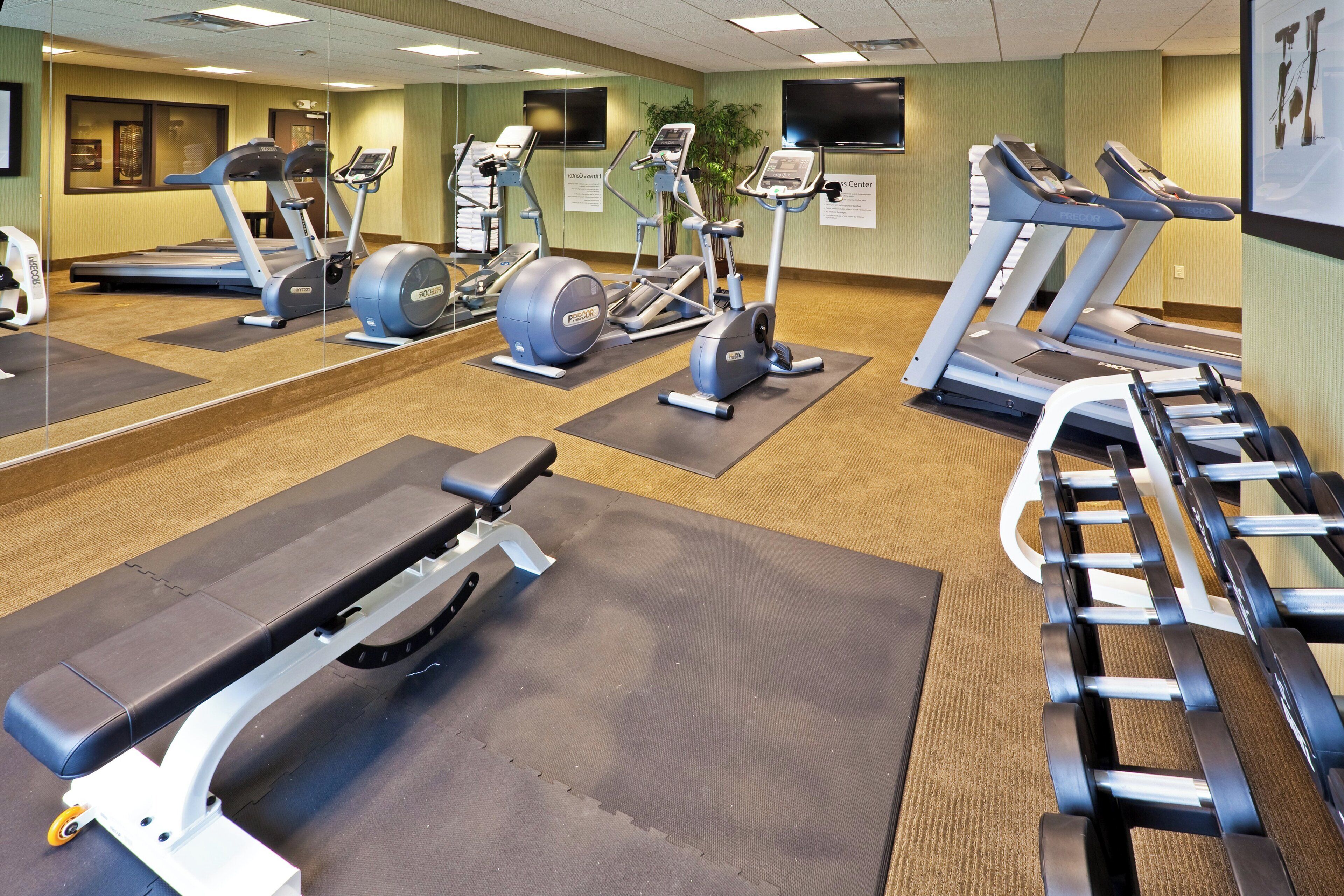Academia com diversos equipamentos de exercício, incluindo esteiras, elípticos e remo.
