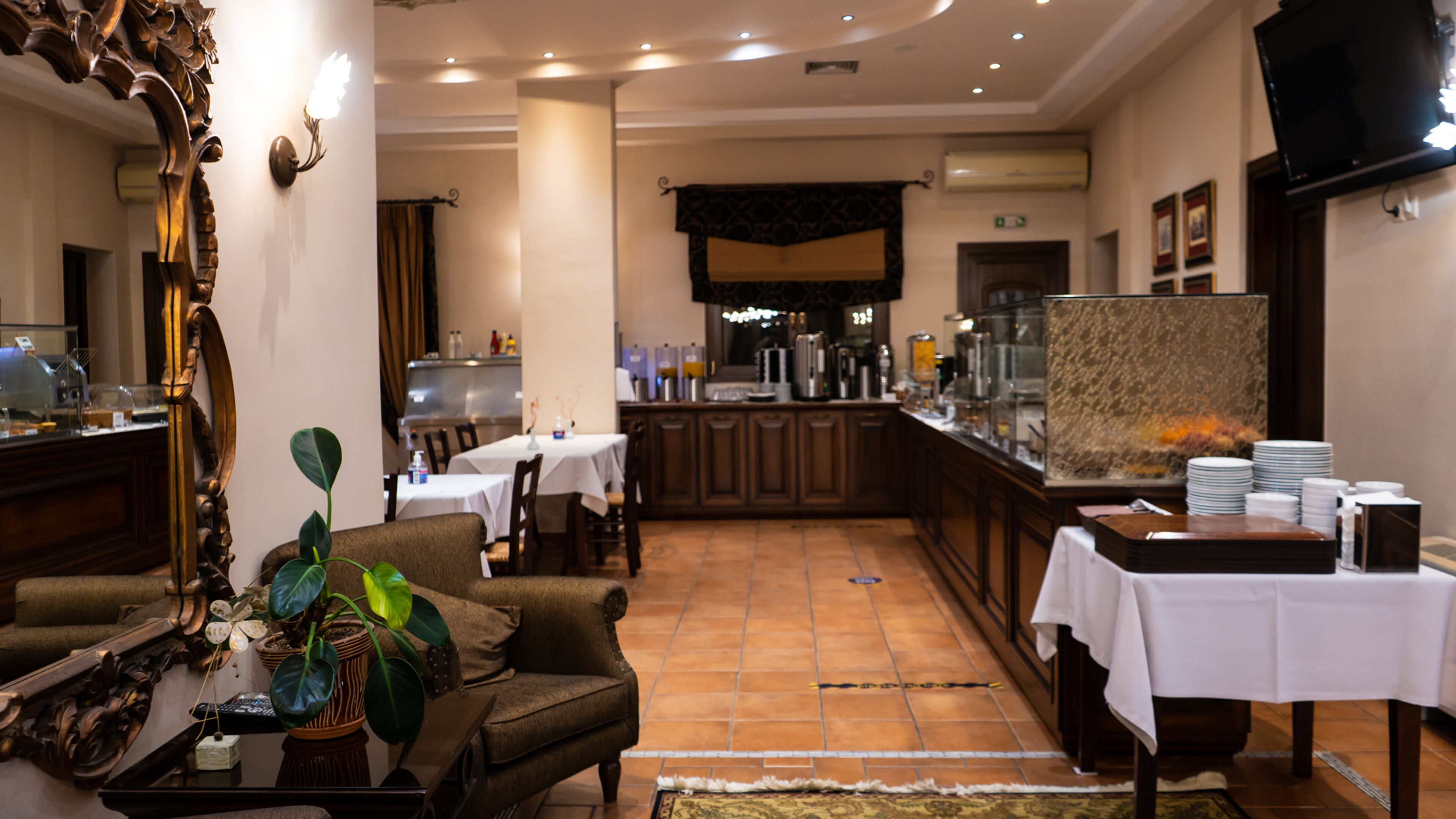 Um saguão de hotel com área de refeições, bar e cozinha ao fundo.