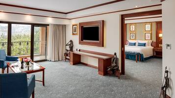 Quarto de hotel com uma cama grande, uma escrivaninha, uma televisão e uma varanda com cortinas.