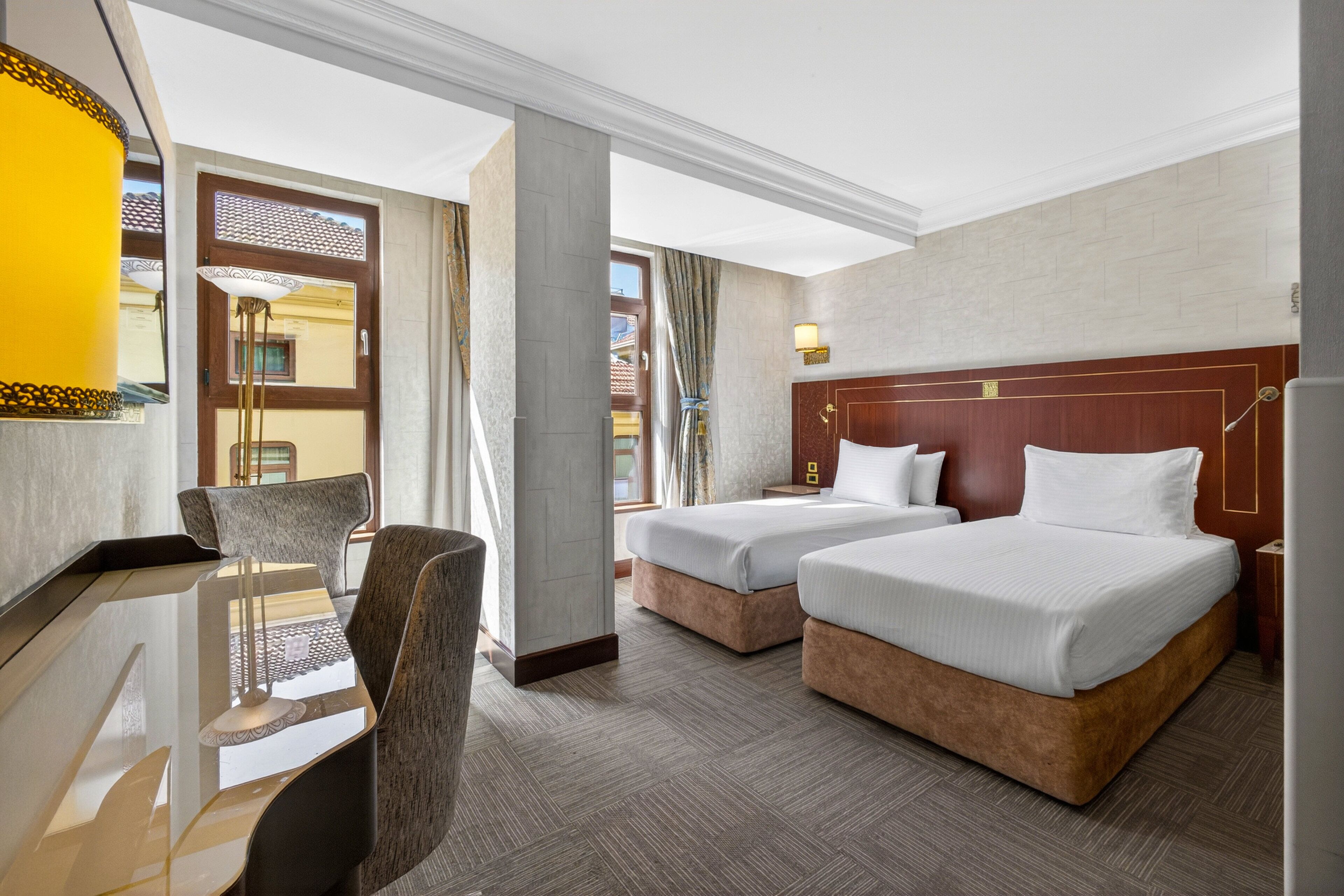 Quarto de hotel com duas camas, uma mesa de jantar e vista para o exterior.