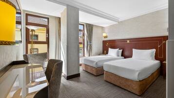 Quarto de hotel com duas camas, uma mesa de jantar e vista para o exterior.