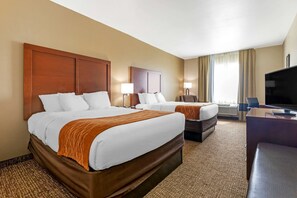 Quarto de hotel com duas camas, uma mesa de trabalho, televisão e janela com cortinas.