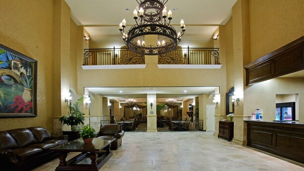 Um hall amplo com um candelabro, uma mesa de recepção e uma área de estar com sofá e mesa de centro.