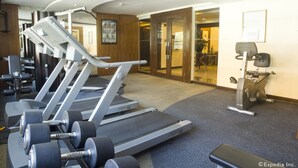 Uma academia com esteiras, halteres e equipamentos de ginástica.