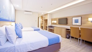 Quarto de hotel com duas camas, uma escrivaninha e uma cadeira.