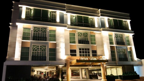 Um hotel de vários andares com uma entrada imponente, grandes janelas e fachada bem iluminada.