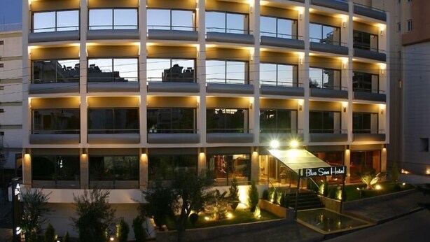 Um hotel de vários andares com design moderno, com varandas em cada pavimento e uma entrada bem iluminada.