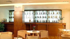 Uma área de bar com cadeiras de vime e um balcão de madeira exibindo garrafas.