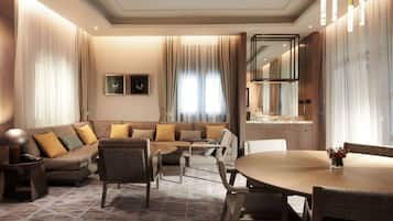 Quarto de hotel moderno com sofá, mesa de jantar, cadeiras e área de cozinha.