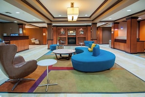 Um hall de entrada com balcão de recepção, área de estar com mesa redonda e lareira.