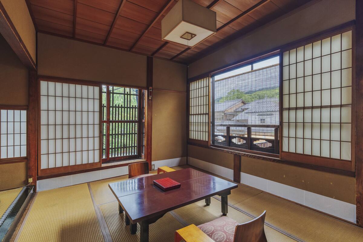 Um quarto japonês tradicional com tatames, uma mesa de madeira e painéis shoji.