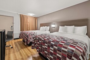 Quarto de hotel com duas camas, uma escrivaninha e uma cadeira.