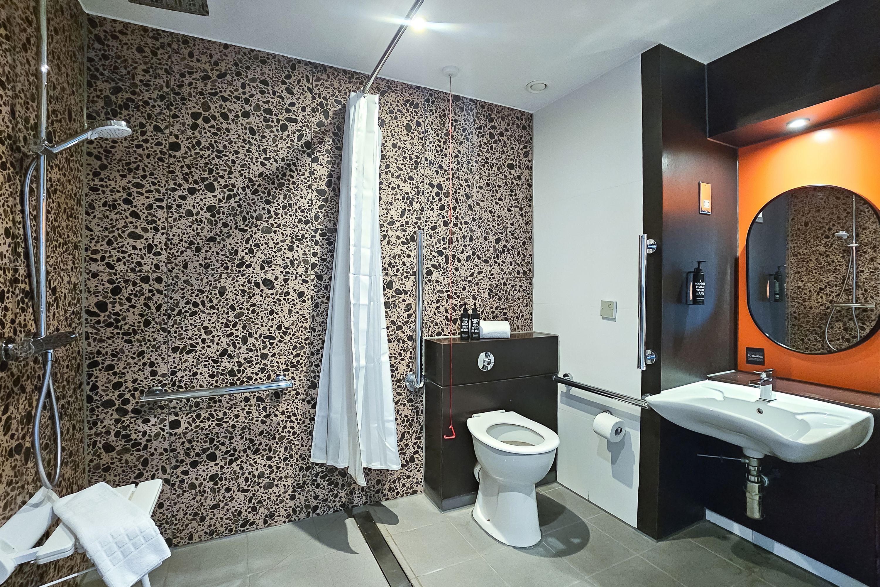 Uma casa de banho moderna com chuveiro, sanita e lavatório.