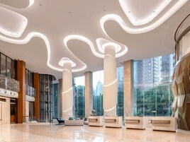 Um lobby moderno com uma receção, área de estar e amplas janelas com vista para a cidade.