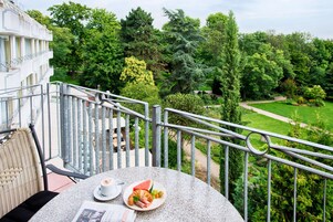 Uma varanda com mesa posta para o café da manhã, com vista para um jardim exuberante e um caminho.