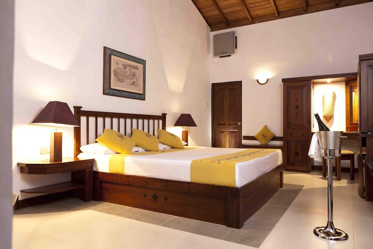 Quarto com cama de madeira, abajures, quadro emoldurado na parede e televisão montada acima da cama.