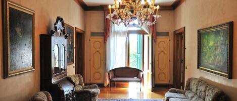 Um quarto com um candelabro, duas poltronas, um sofá, um tapete grande e um armário.