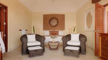 Um quarto com duas cadeiras de vime, uma mesa central e um objeto decorativo fixado na parede.