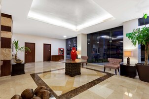 Um hall com uma mesa redonda central, área de estar e balcão de recepção.