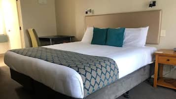 Quarto de hotel com cama, escrivaninha e cadeira.