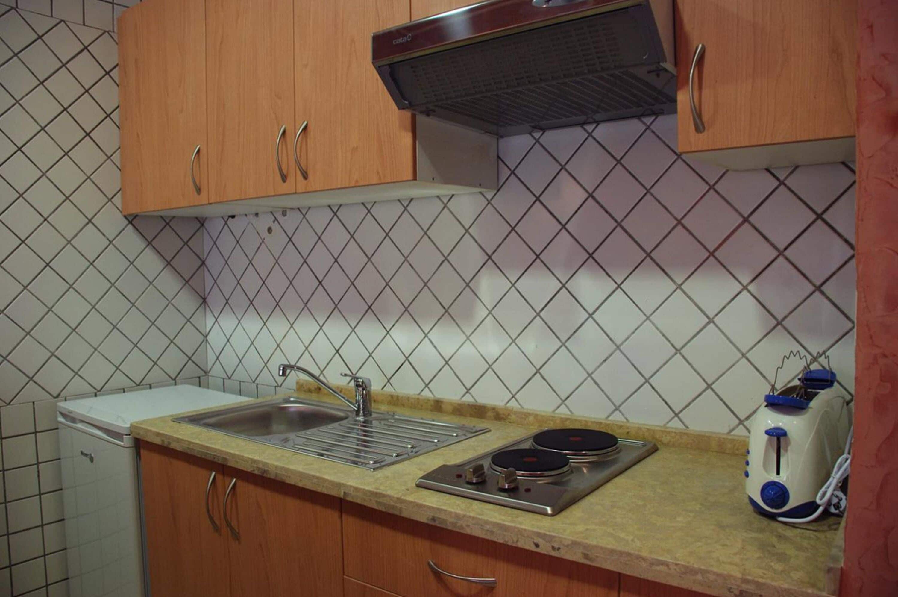 Cozinha com armários de madeira, pia, fogão e torradeira.