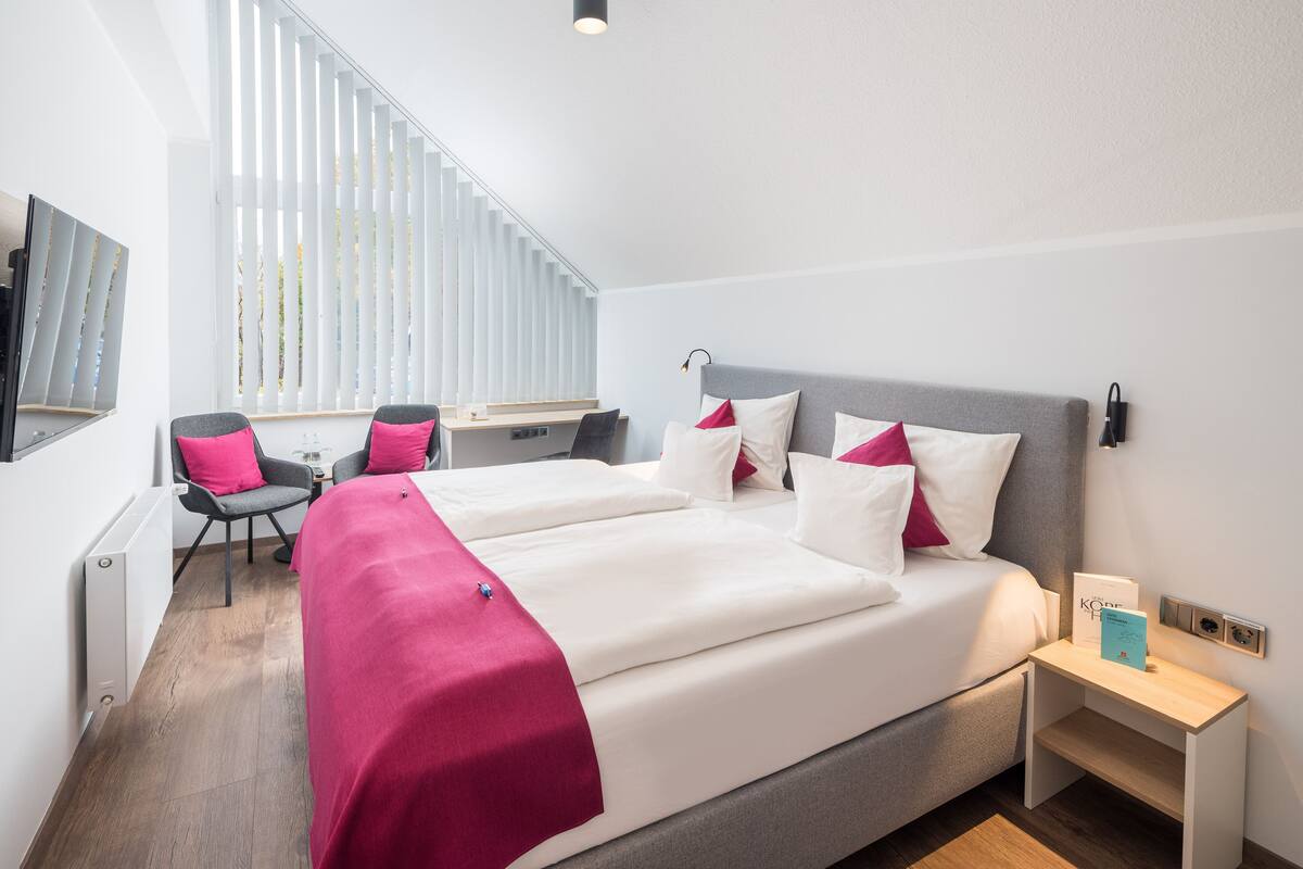 Quarto de hotel moderno com uma cama grande, uma escrivaninha e uma cadeira.