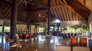 Um hall amplo com teto alto, área de bar central e disposição de assentos.