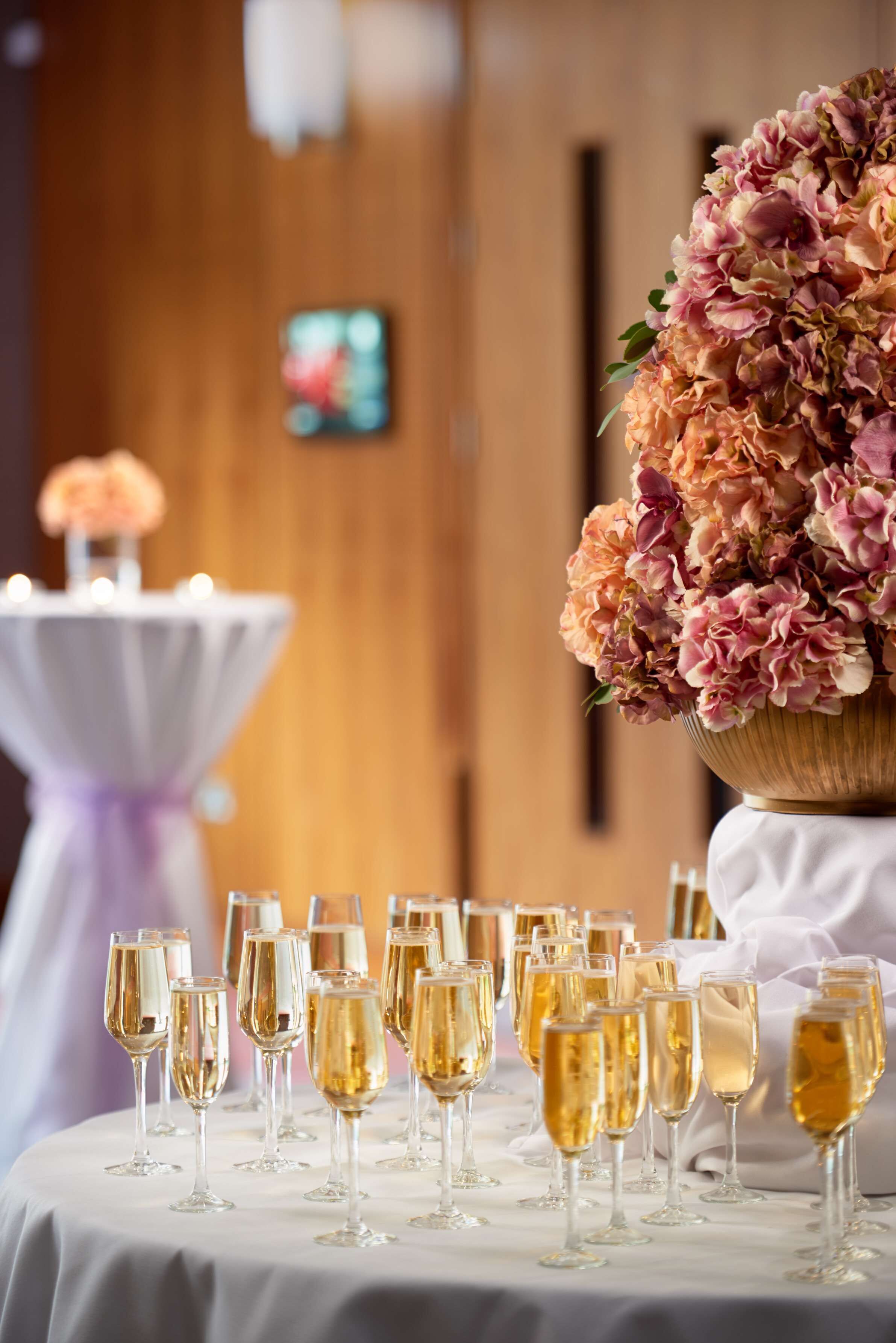 Uma mesa com taças de champanhe e um arranjo floral grande.