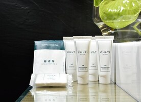 Exposição de tubos de gel de banho e shampoo CUFFIA DOCCIA, juntamente com um sabonete em uma superfície reflexiva com fundo escuro.