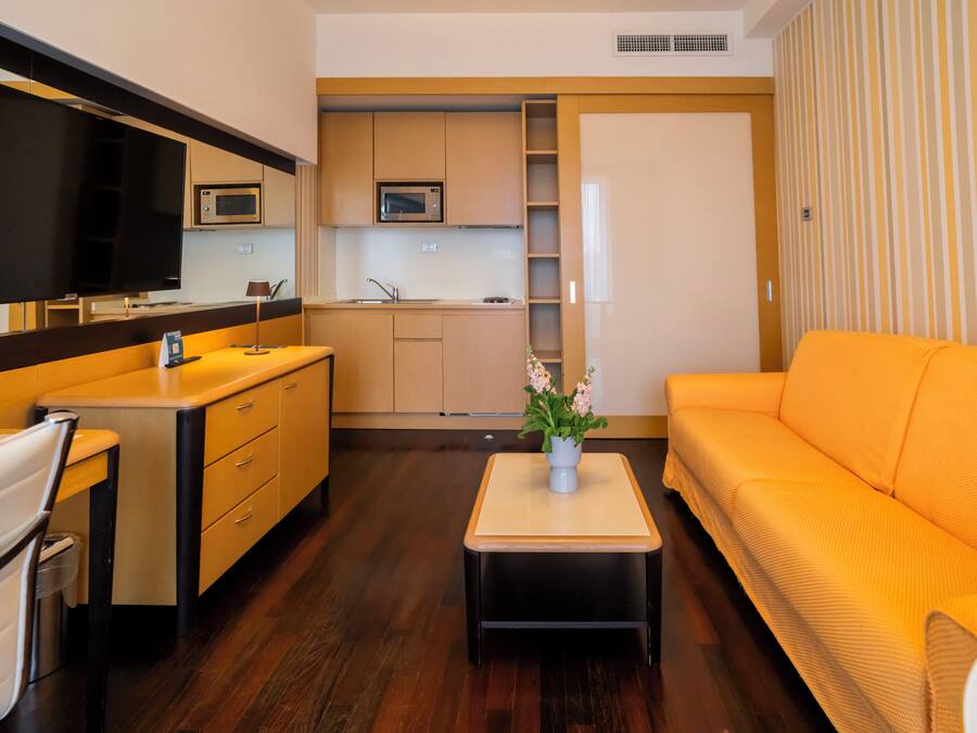 Um espaço compacto com cozinha compacta, sofá, mesa pequena e TV.
