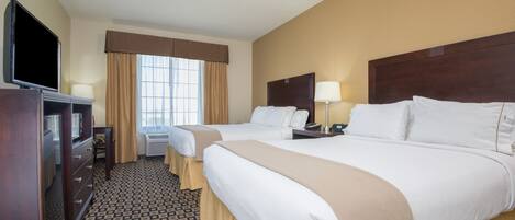 Quarto de hotel com duas camas, televisão, escrivaninha e janela com cortinas.